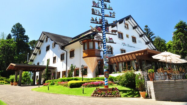 Um edifício tradicional com telhado inclinado, varanda com grade e placa indicando que é um hotel.