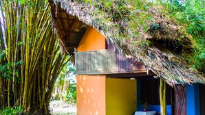 Uma cabana de bambu tradicional com telhado de palha, rodeada por vegetação exuberante.