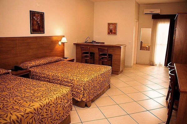 Quarto de hotel com duas camas, uma escrivaninha e uma cadeira.