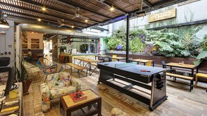 Um espaço interior acolhedor com mesa de pingue-pongue, assentos confortáveis e área de bar.