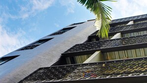 Um edifício moderno com fachada geométrica única, grandes janelas e uma palmeira.