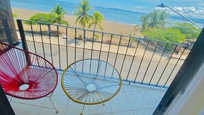 Uma varanda com vista para uma praia e palmeiras.
