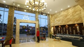 Um hall amplo com um grande candelabro, uma área de estar com um sofá e um balcão de recepção.