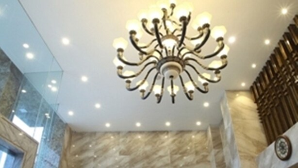 Um hall amplo com um lustre grande, paredes de mármore e uma área de estar com sofás.
