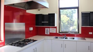 Uma cozinha com exaustor de aço inoxidável, uma janela com persianas e uma pia.