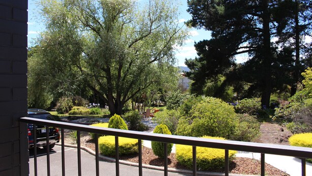 Varanda com vista para um jardim ajardinado, incluindo várias árvores e arbustos.