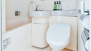 Casa de banho moderna com lavatório branco, sanita e espelho. Existem produtos de higiene pessoal no lavatório e um porta-toalhas acima.
