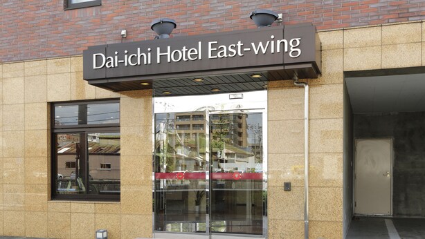 Entrada da ala East do Hotel Dai-ichi, com portas de vidro e fachada de tijolos.