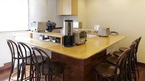 Cozinha com ilha central, banquetas de bar e diversos eletrodomésticos, incluindo cafeteira e micro-ondas.
