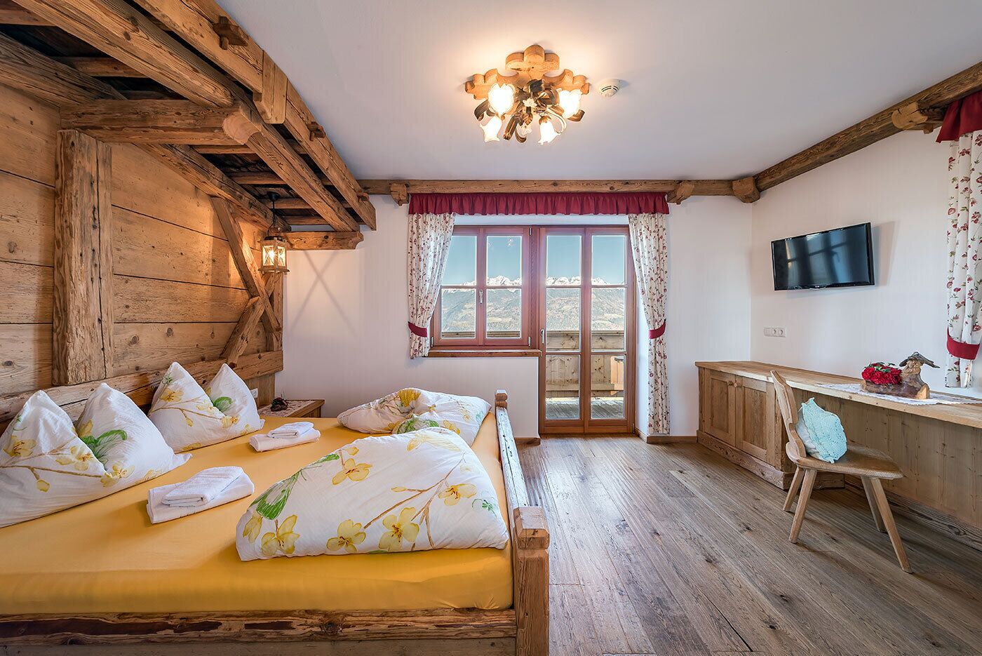 Um quarto rústico de madeira com uma cama, uma escrivaninha e uma televisão.