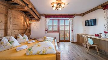 Um quarto rústico de madeira com uma cama, uma escrivaninha e uma televisão.