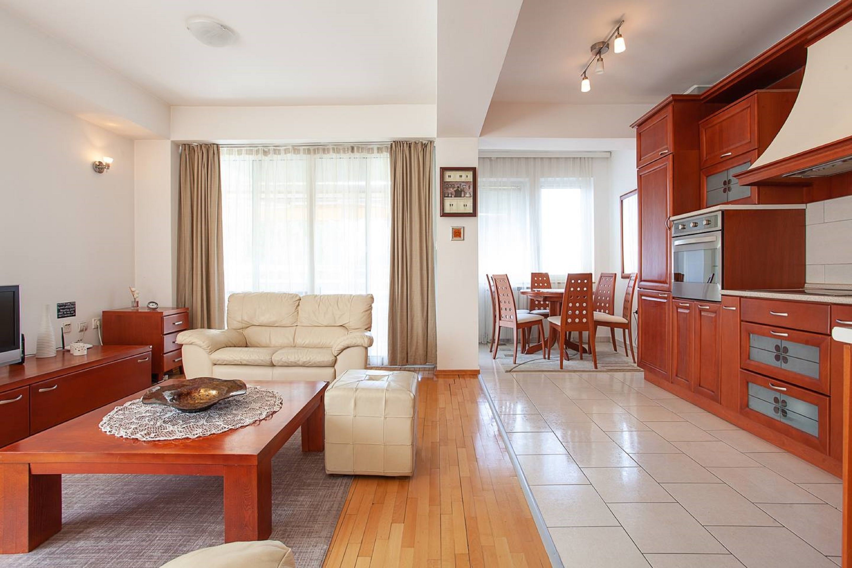 Uma sala de estar moderna com um sofá, uma mesa de centro e uma área de jantar com cadeiras e uma mesa.