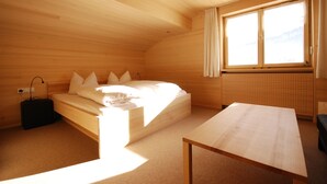 Um quarto de cabana acolhedor, com uma cama, uma mesa e uma janela com cortinas.