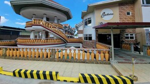 Um hotel com uma estrutura circular central, uma escadaria com balaústres amarelos e uma placa com a inscrição 'Candelaria'.
