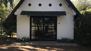 Um edifício térreo com telhado em duas águas, uma grande porta de vidro e uma pequena varanda.
