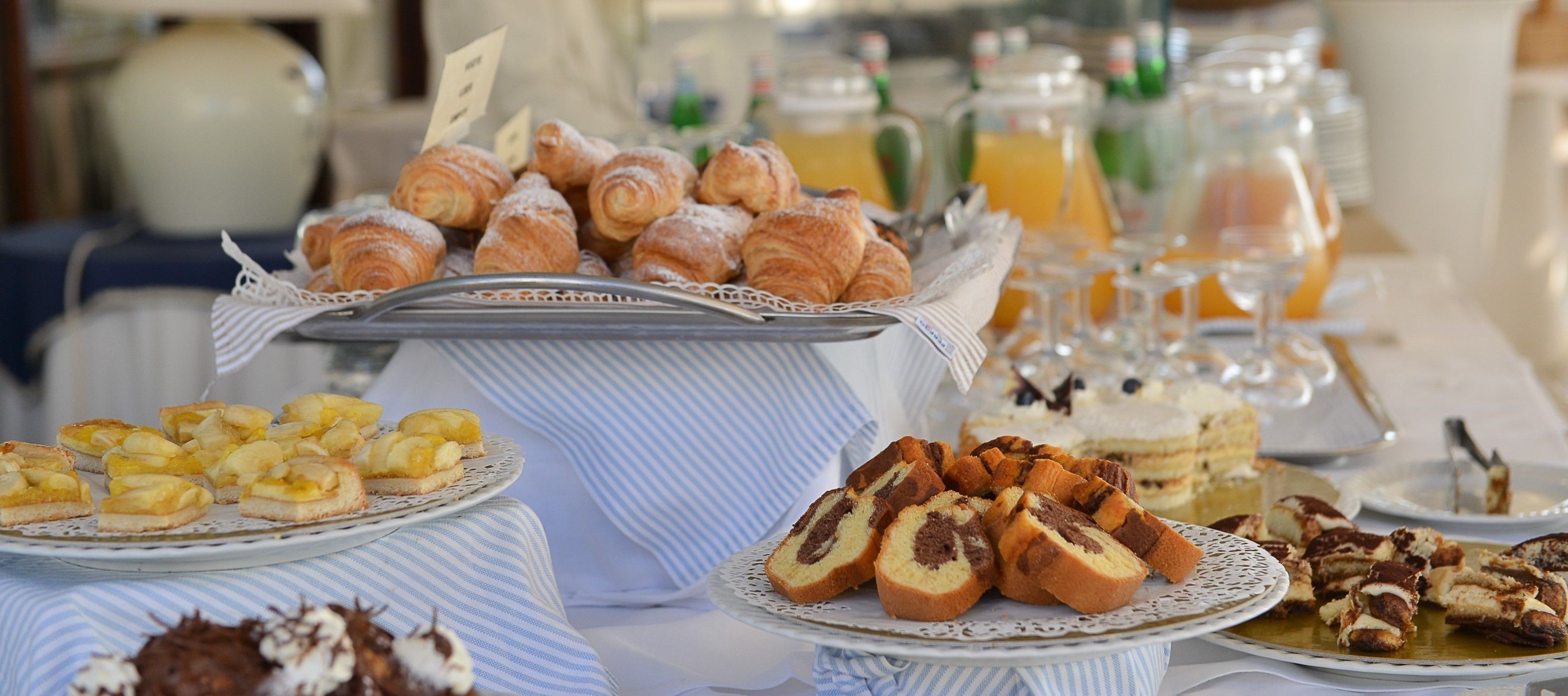 Uma mesa de buffet com pastelaria, bolos e bebidas.