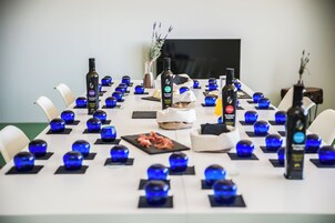 Uma sala de conferências com uma mesa comprida, ornamentos de vidro azul e garrafas de bebidas.