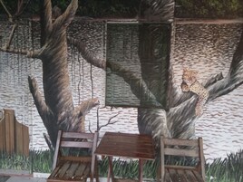 Um mural com um leopardo em uma árvore, bancos de madeira e uma parede estampada.