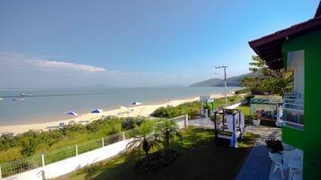 Um imóvel à beira-mar com vista para o mar, um jardim cercado e um edifício com fachada verde.