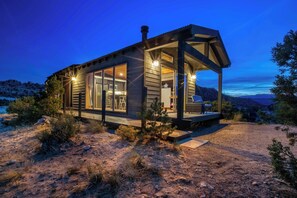Uma cabana moderna com grandes janelas, um deck e uma vista panorâmica.