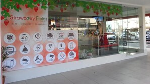 Hotel com grande vitrine exibindo comodidades como quarto decorado, recepção 24 horas, WiFi gratuito e água de cortesia.