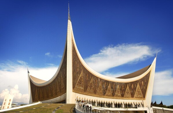 Um edifício grande e moderno com telhado curvo e padrões elaborados na fachada.