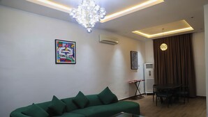 Uma sala de estar moderna com um sofá verde, uma mesa de centro de vidro e um espaço de jantar com mesa e cadeiras.