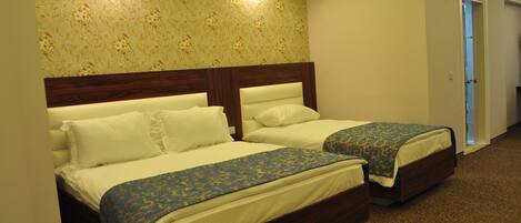 Quarto de hotel com duas camas, papel de parede floral e piso coberto por carpete.
