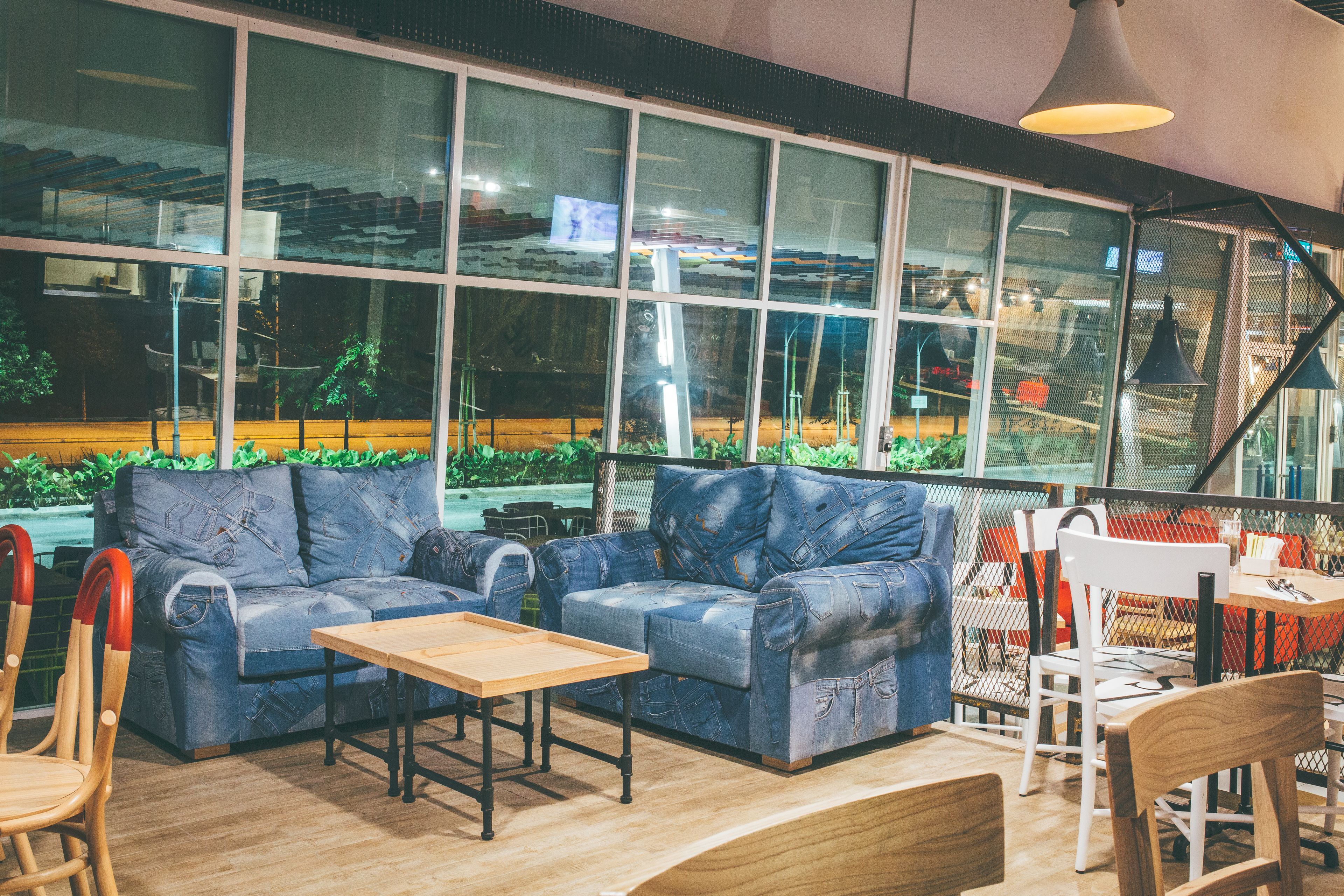 Espaço de estar moderno e interno, com uma janela grande, sofá, mesa e cadeiras.