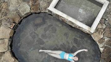 Uma pessoa deitada em uma superfície de pedra com uma piscina retangular ao lado.