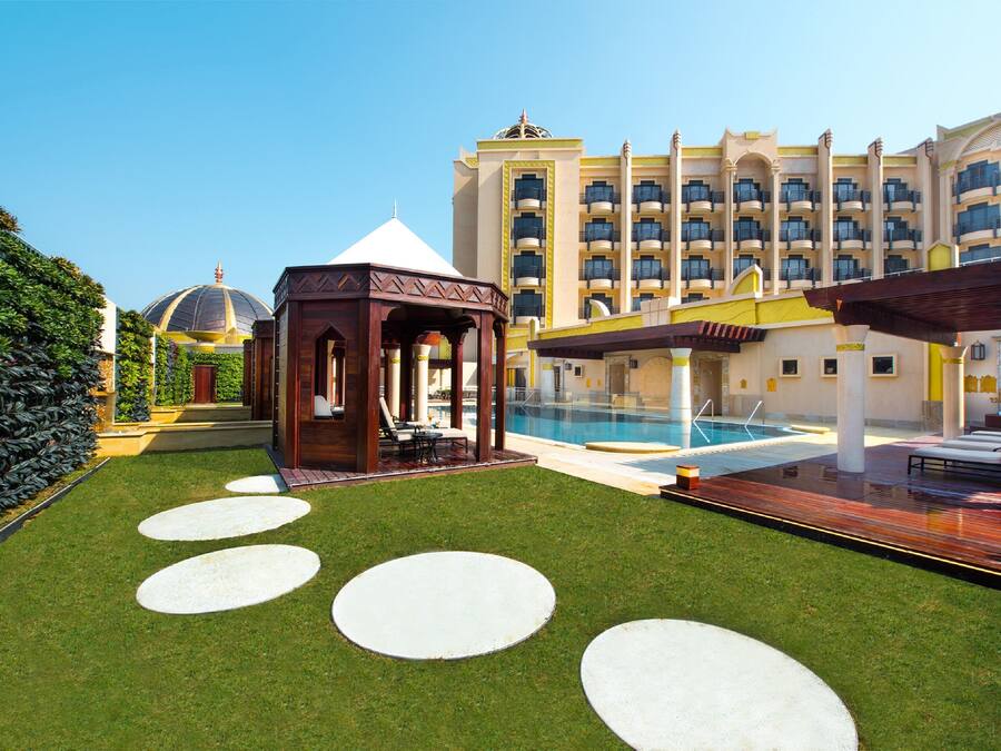 Um hotel com piscina, um gazebo e um gramado bem cuidado com pedras para caminhar.