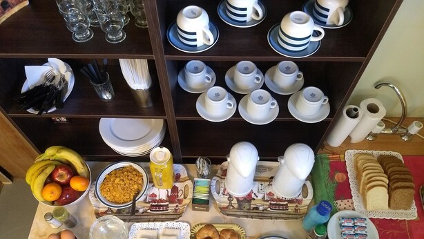 Um buffet de café da manhã com diversos alimentos, pratos e copos.
