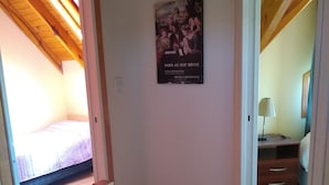 Uma escadaria com guarda-corpos de madeira leva a um quarto com uma cama e uma mesa de cabeceira.