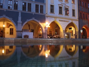 Um edifício histórico com entradas em arco e reflexo na água.