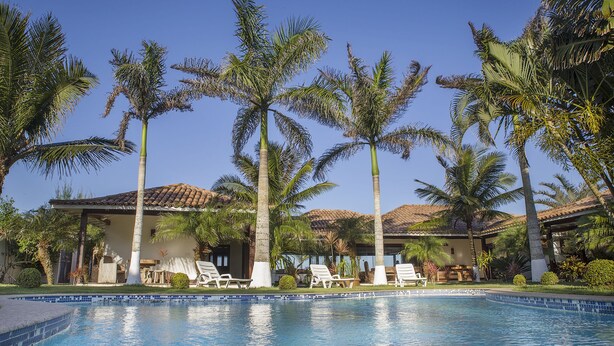Uma área de piscina com espreguiçadeiras e palmeiras.
