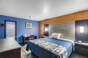Quarto de hotel com cama, escrivaninha e cadeira.