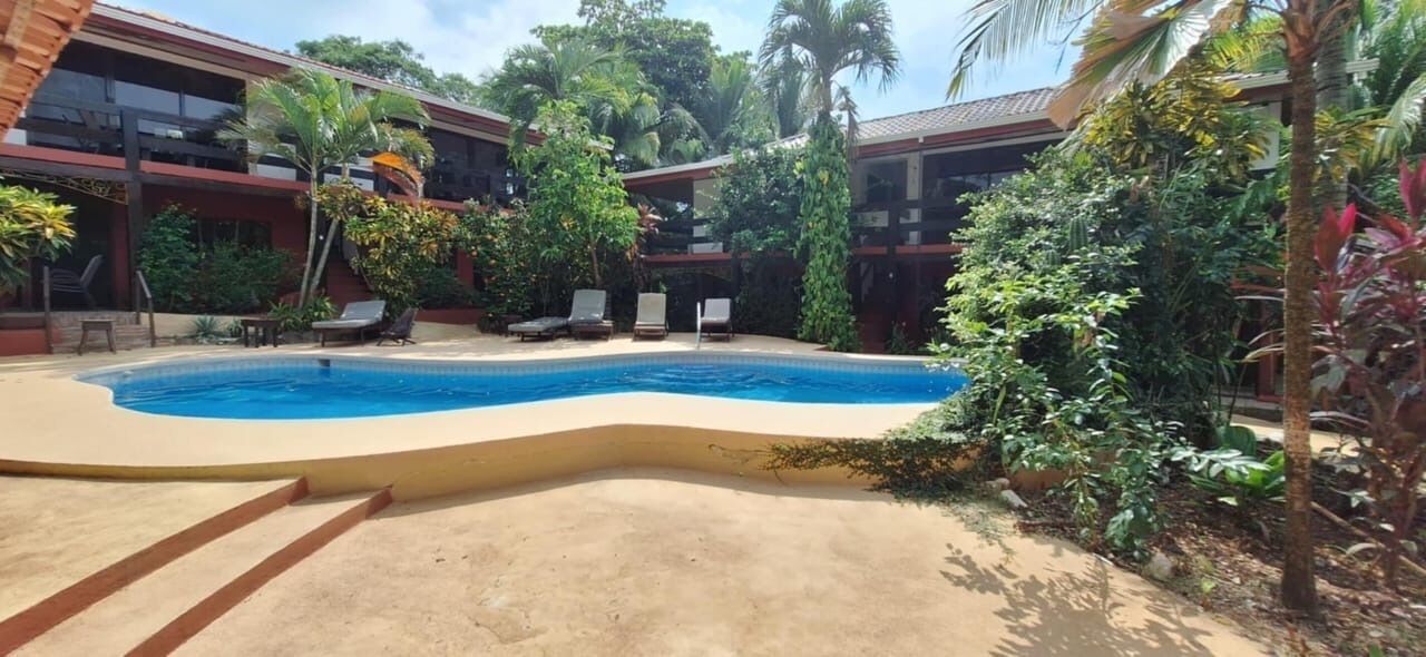 Piscina com espreguiçadeiras e escadaria que leva a um edifício.