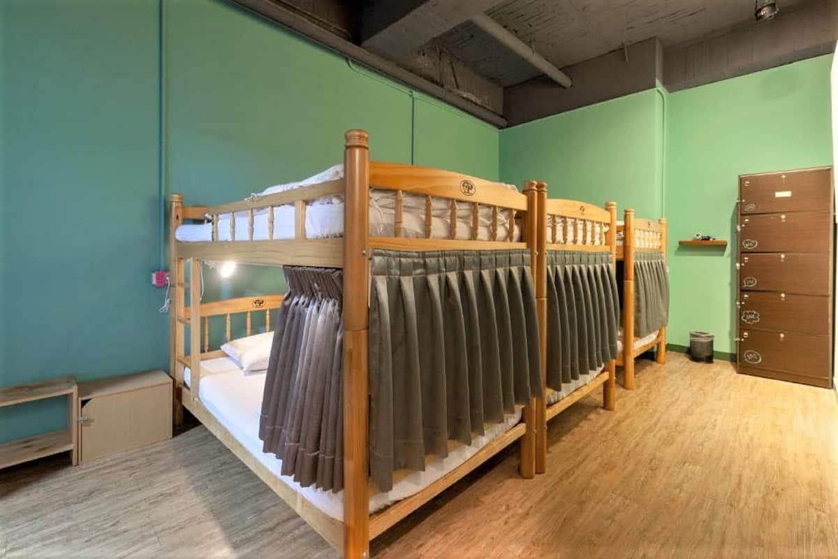 Quarto com beliche, cabeceira de madeira, prateleira pequena e guarda-roupa.