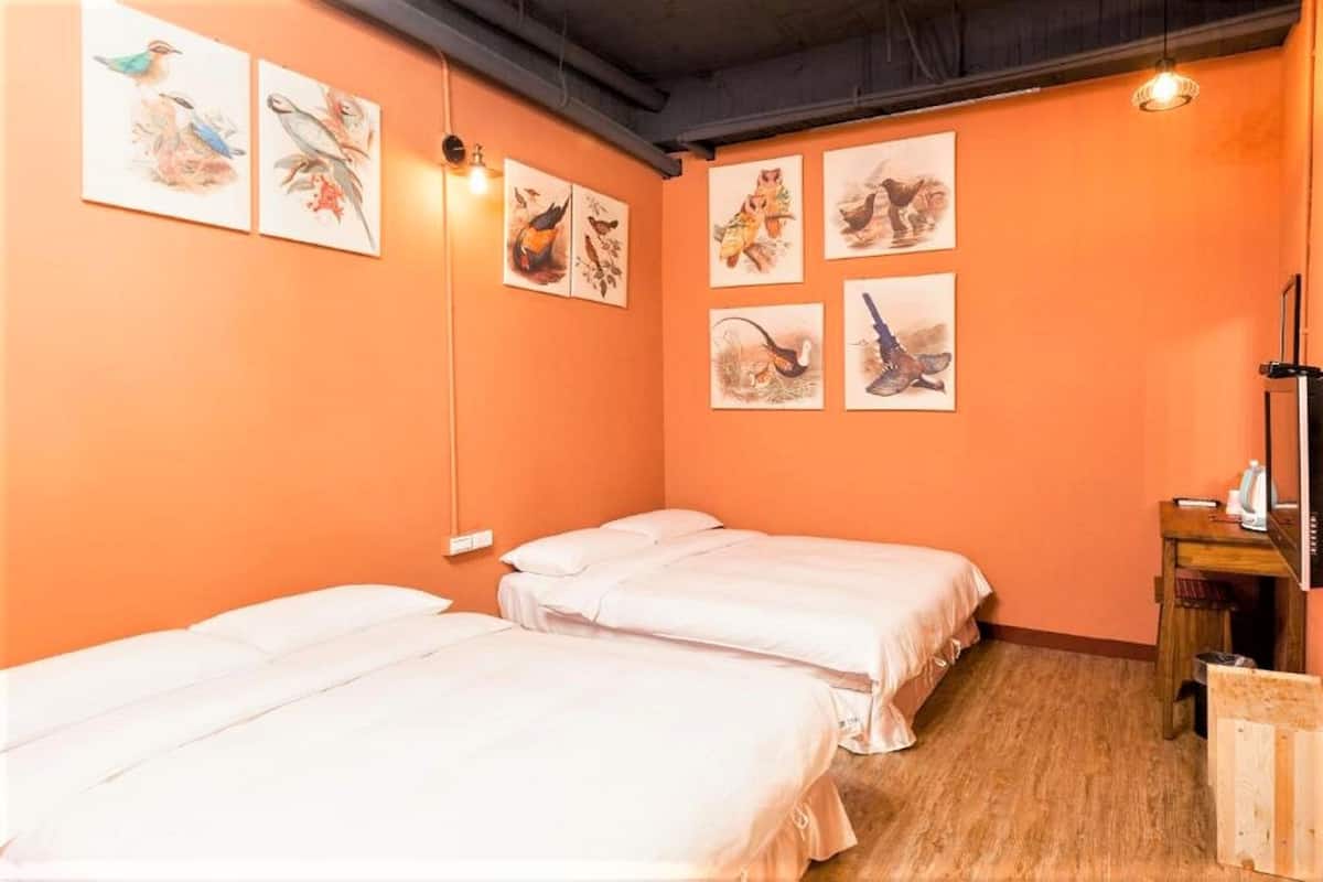 Quarto com duas camas, paredes alaranjadas e várias pinturas de pássaros.