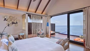 Quarto espaçoso com uma cama grande, área de estar com vista para o mar e varanda com deck de madeira.