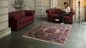 Um quarto espaçoso com dois sofás de couro vermelho, um tapete estampado e uma luminária.
