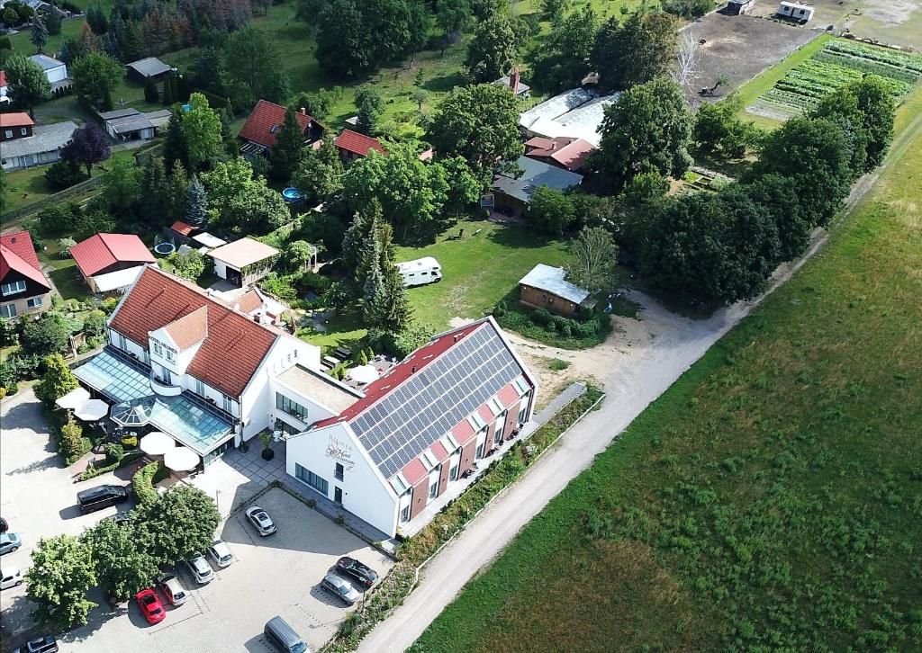 Vista aérea de uma área residencial com várias casas, um edifício grande com painéis solares no telhado e um estacionamento.