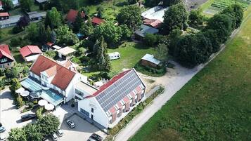 Vista aérea de uma área residencial com várias casas, um edifício grande com painéis solares no telhado e um estacionamento.