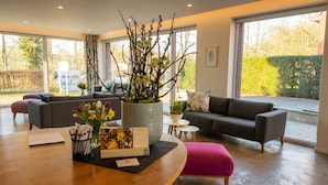 Uma sala de estar moderna com uma janela grande, um sofá, uma mesa de centro e um vaso com flores.