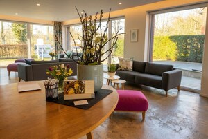 Uma sala de estar moderna com uma janela grande, um sofá, uma mesa de centro e um vaso com flores.