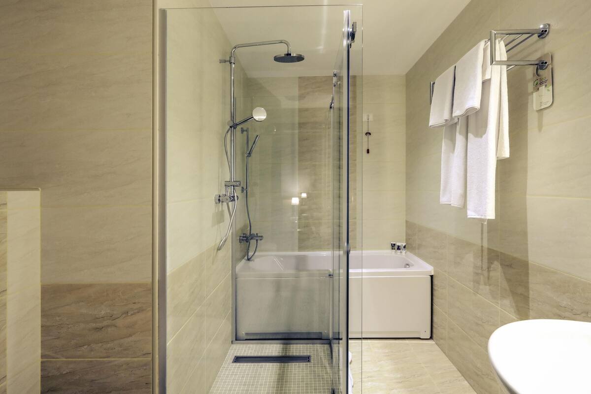 Um banheiro moderno com chuveiro em cabine de vidro, banheira branca e piso revestido com azulejos.