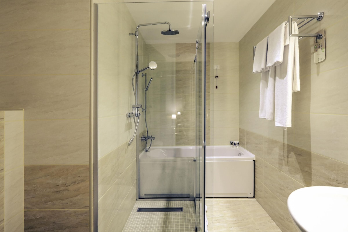 Um banheiro moderno com chuveiro em cabine de vidro, banheira branca e piso revestido com azulejos.