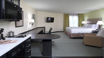 Quarto de hotel com cama, escrivaninha, cadeira, televisão e máquina de café.