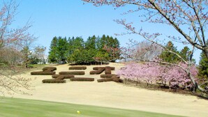 Um campo de golfe com bunkers de areia e céu limpo.
