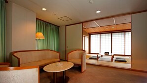 Quarto com sofá, cadeiras, uma mesinha e vista através de um painel shoji.